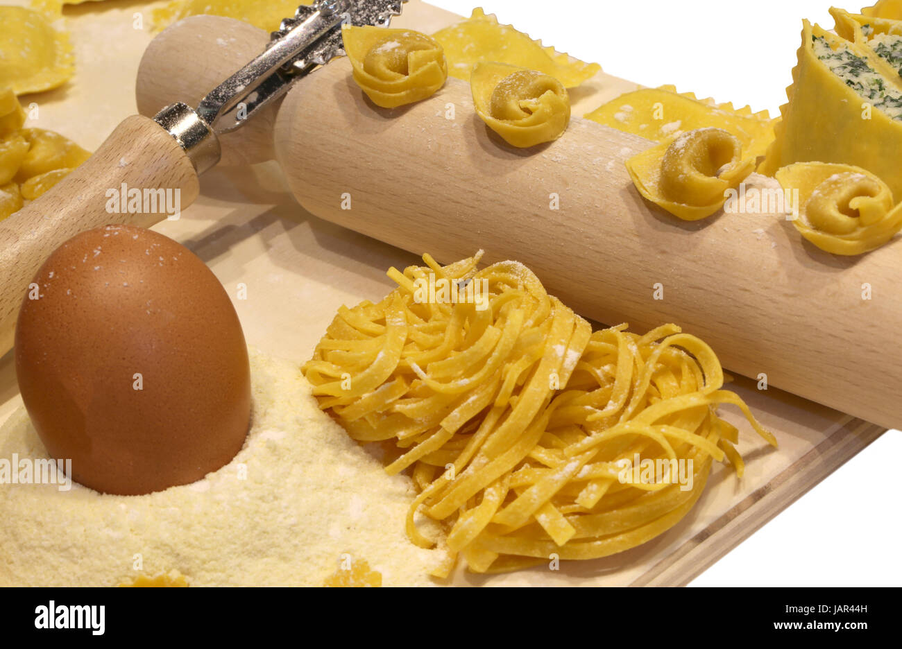 Fresh italian pasta of many sizes with wooden rolling pin and ...