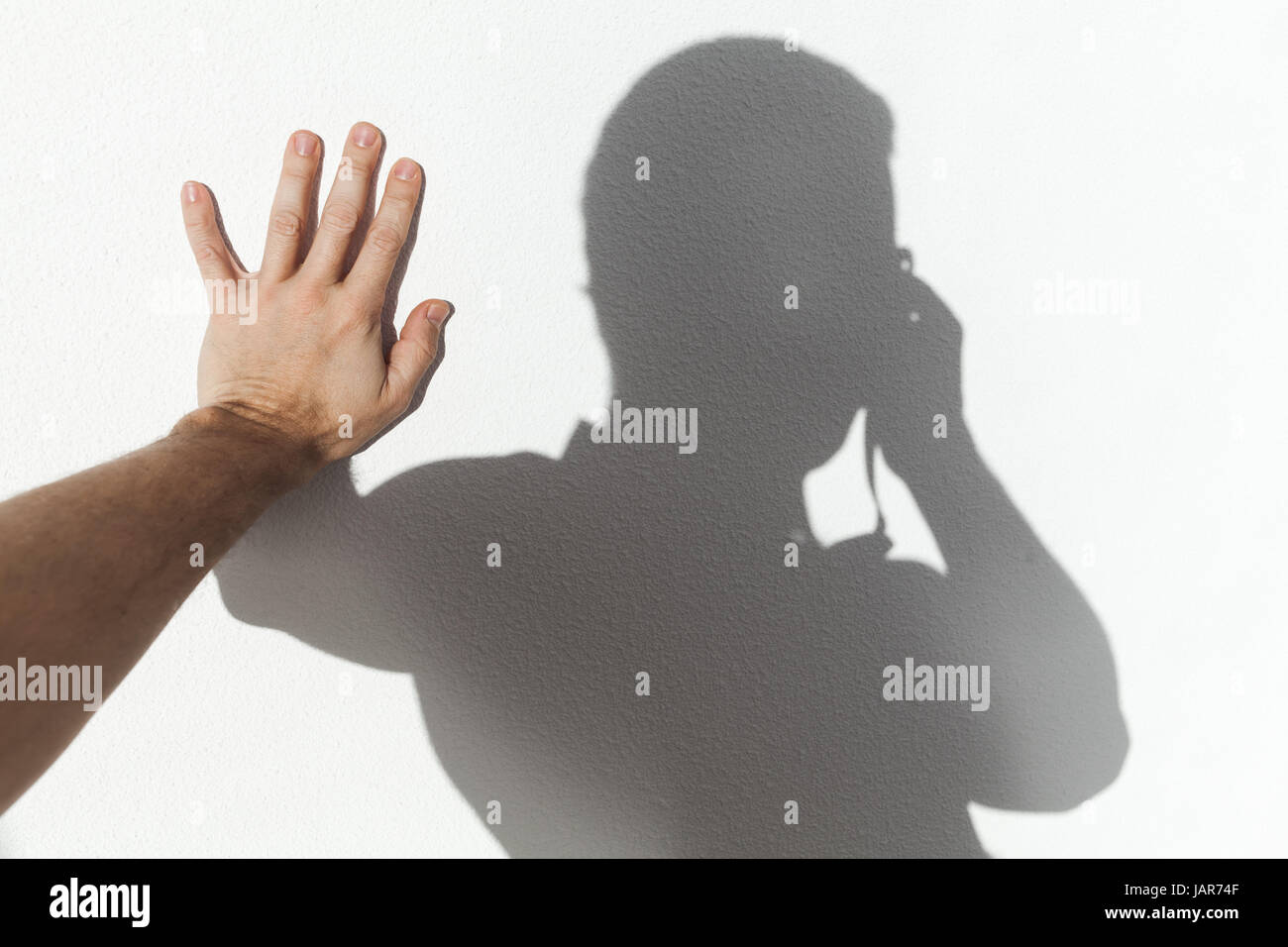 Man touching his shadow on white wall and taking photo Stock Photo - Alamy