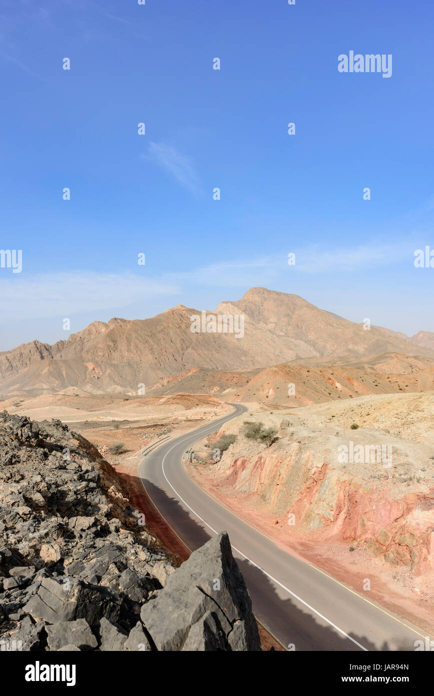 A road stretches through Oman’s arid landscape with rugged mountains ...