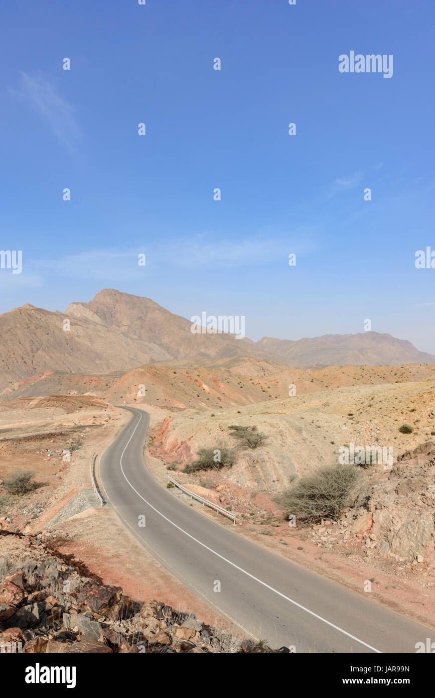 Vertical view of a road winding through Oman’s arid wadi landscape with ...