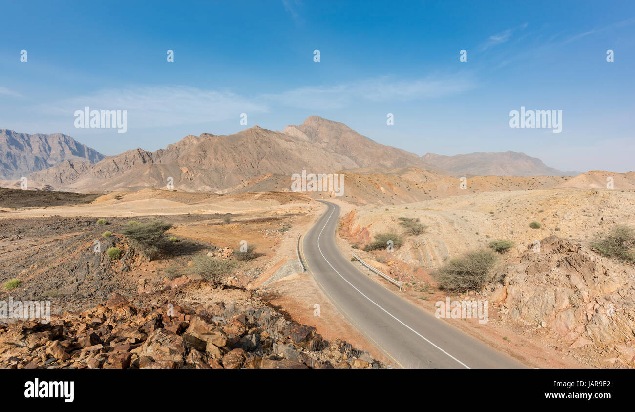 Panoramic view of a road through Oman’s arid wadi landscape, with arid ...