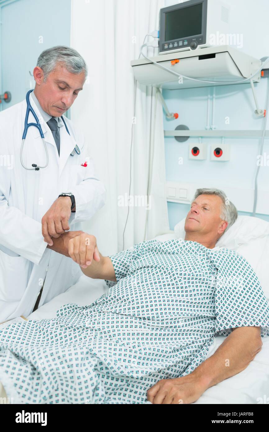 Doctor measuring the pulse of a male patient Stock Photo - Alamy