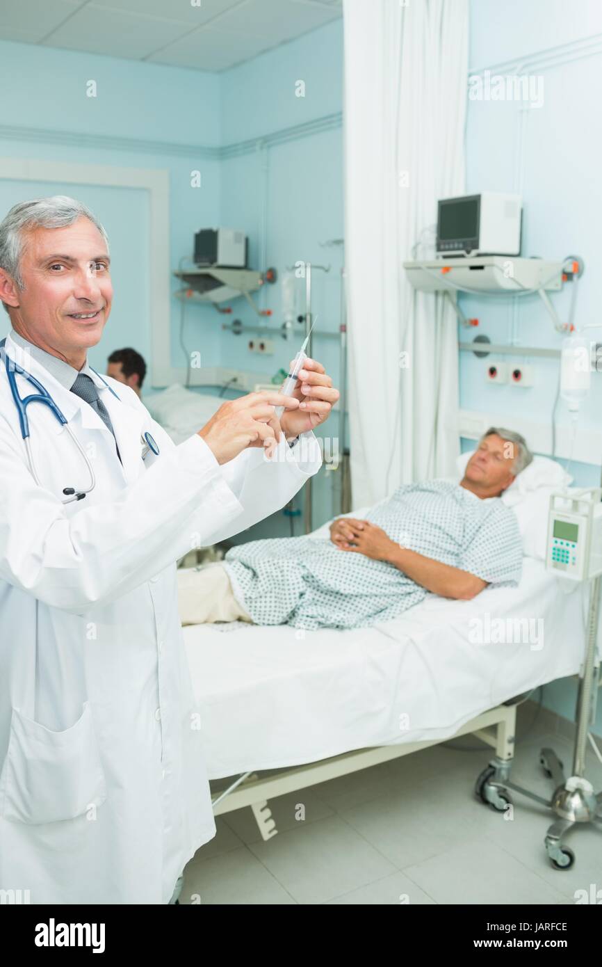 Happy doctor holding an injection Stock Photo - Alamy