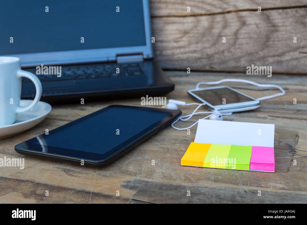 Modern laptop, tablet, mobile phone and sticky notes on the table ...