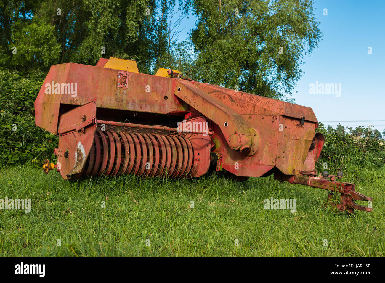 One rusty old hay baler rest in grass pastures Stock Photo - Alamy