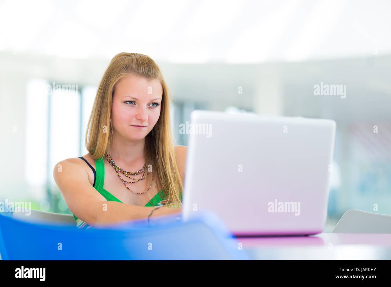 pretty female college student working on her laptop computer on campus ...