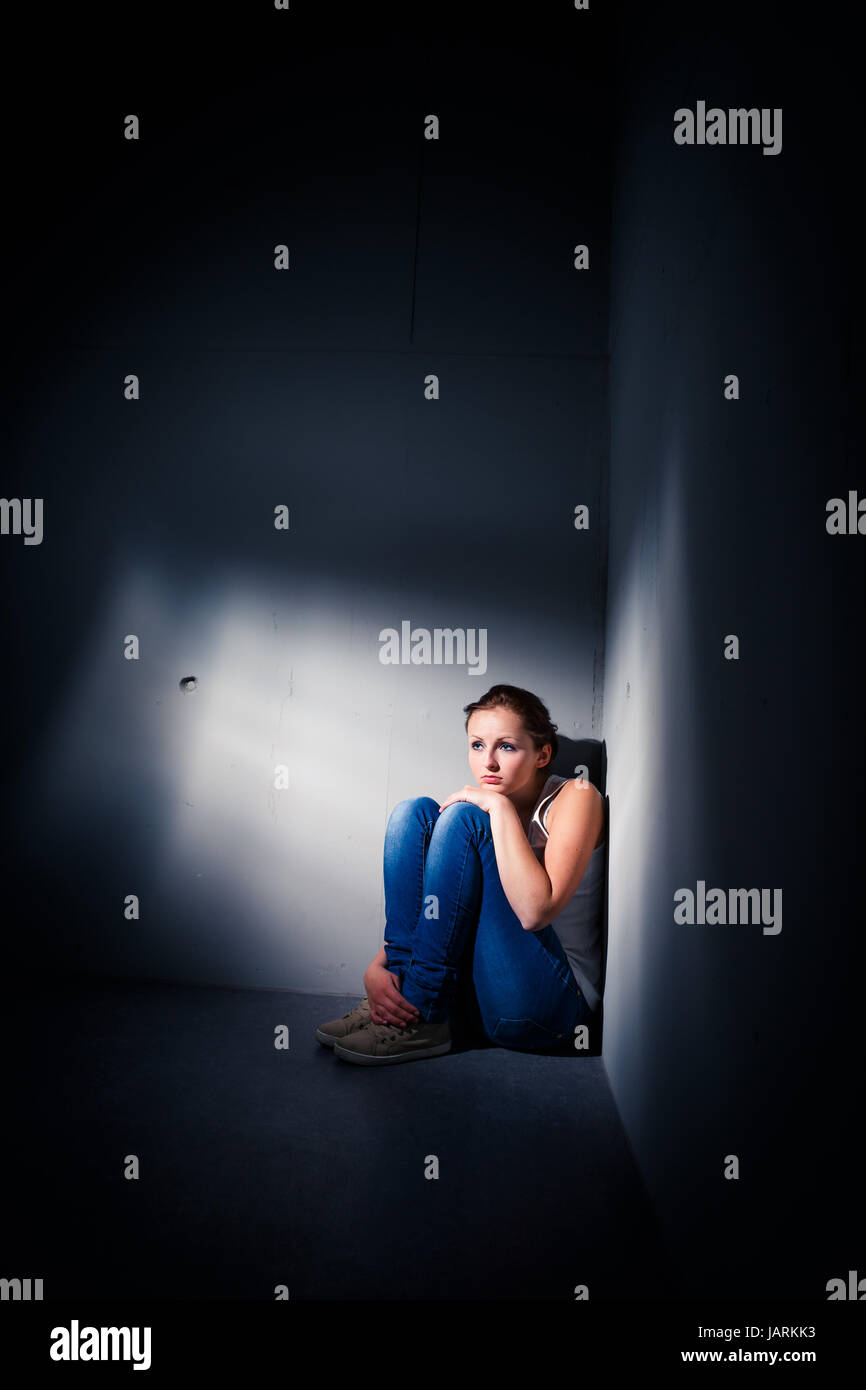 Young woman suffering from a severe depression (very harsh lighting is ...