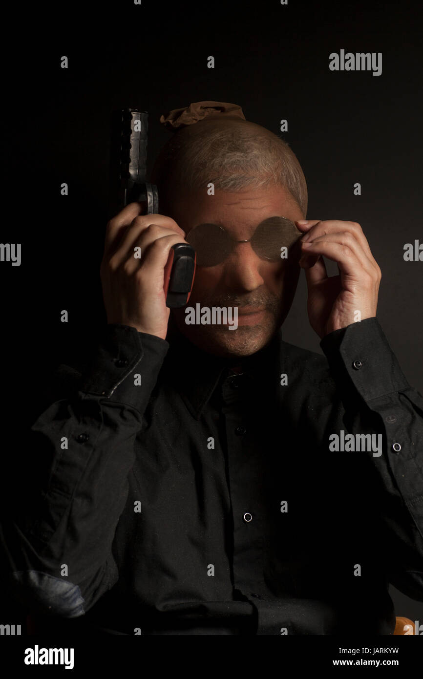 criminal bandit man wearing a stocking mask holds a gun in his hand on ...