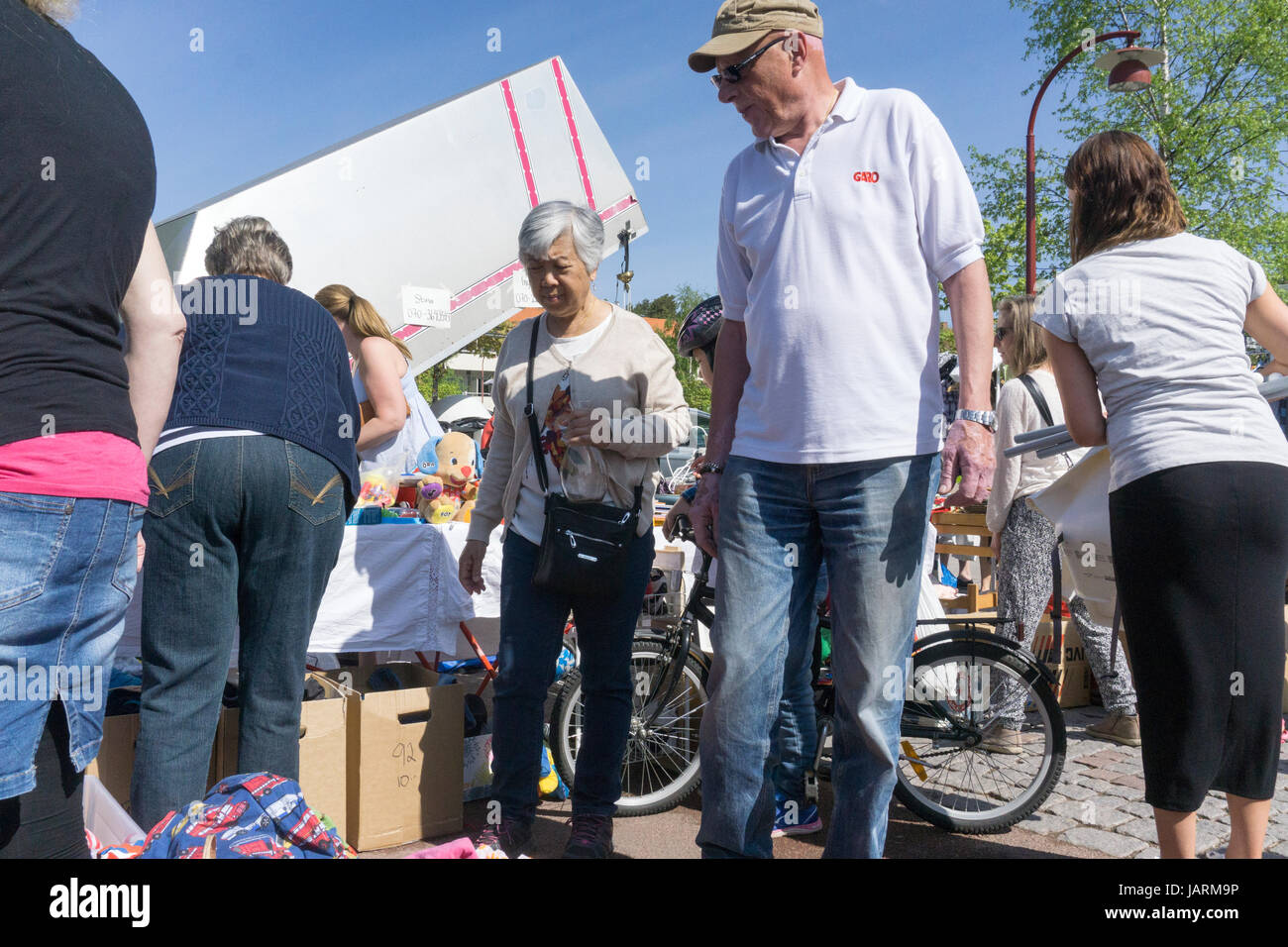 People browsing clothes and household items at an outdoor market or car ...