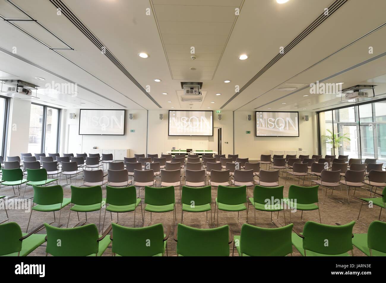 Rows of chairs facing three large screen in conference room Stock Photo ...