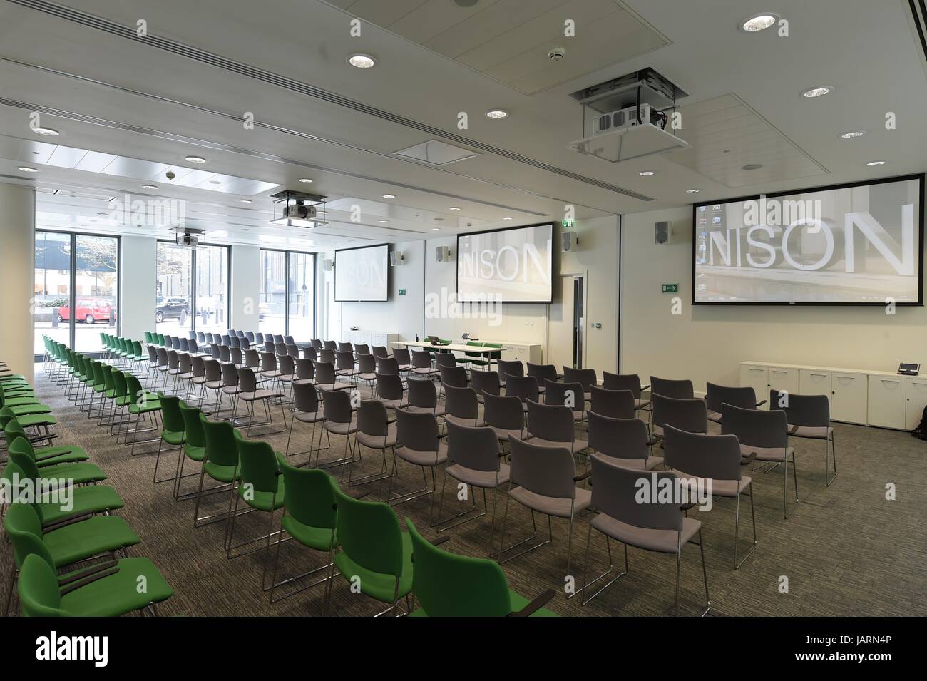 Rows of chairs facing three large screen in conference room Stock Photo ...