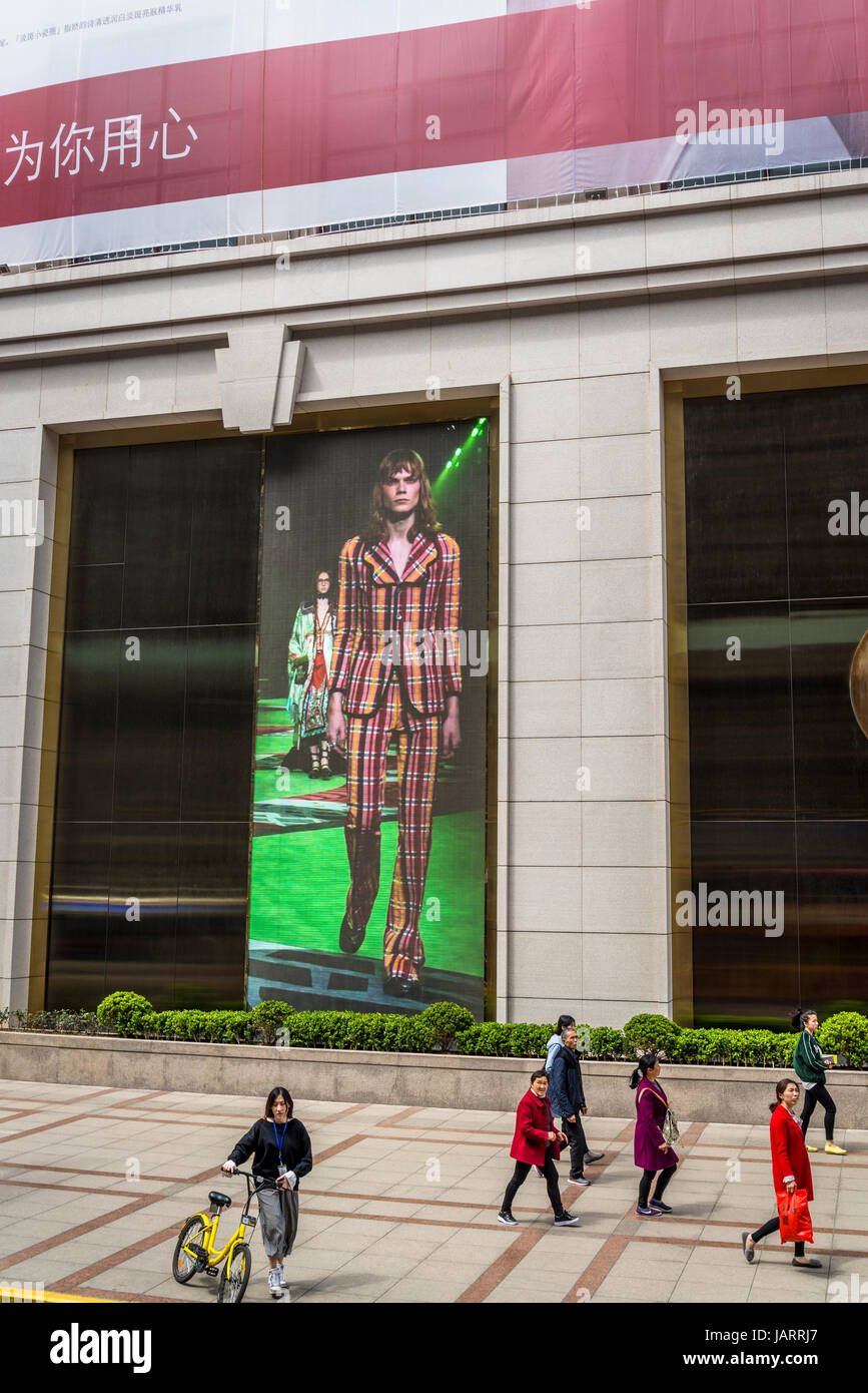 Huge advertising moving image hoarding towering over pedestrians in ...