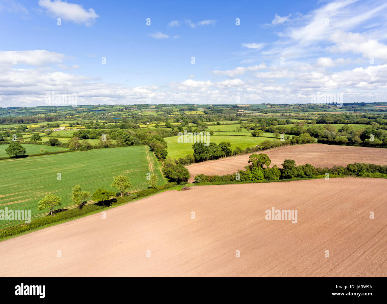 Aerial view of farm fields with ploughed brown fields, green pastures ...