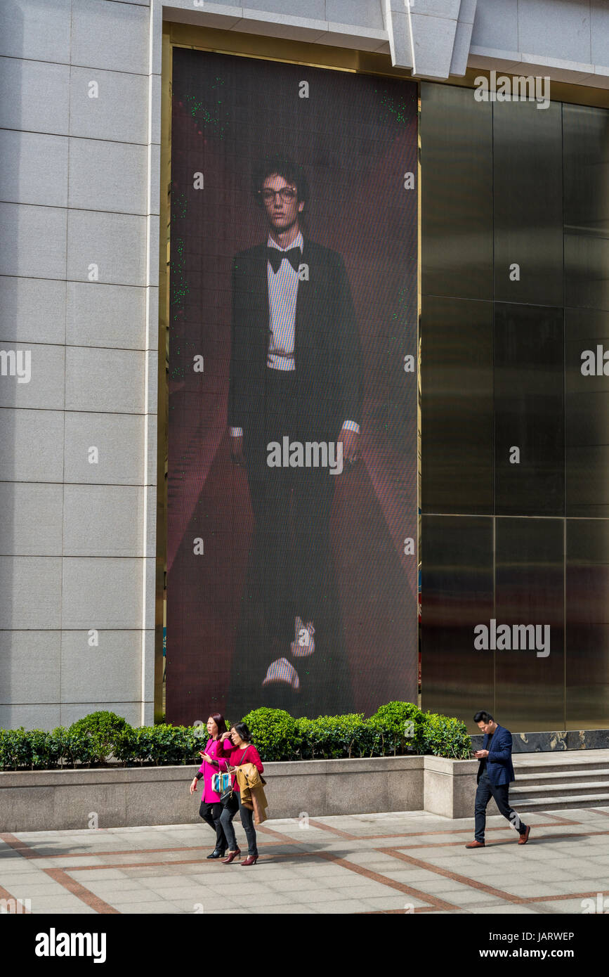 Huge advertising moving image hoarding towering over pedestrians in ...