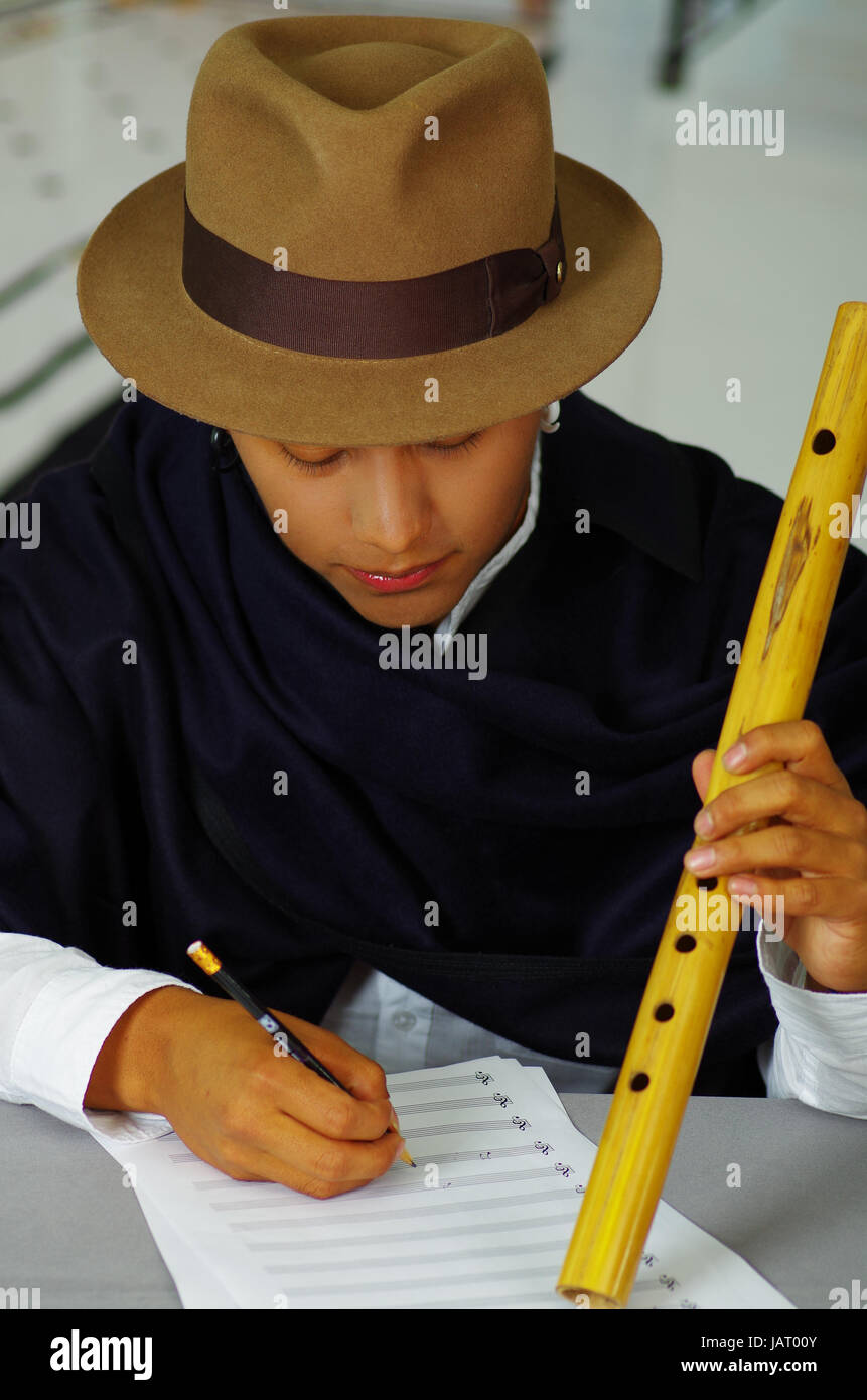 Indigenous young latin man writing notes to music with quena flute ...