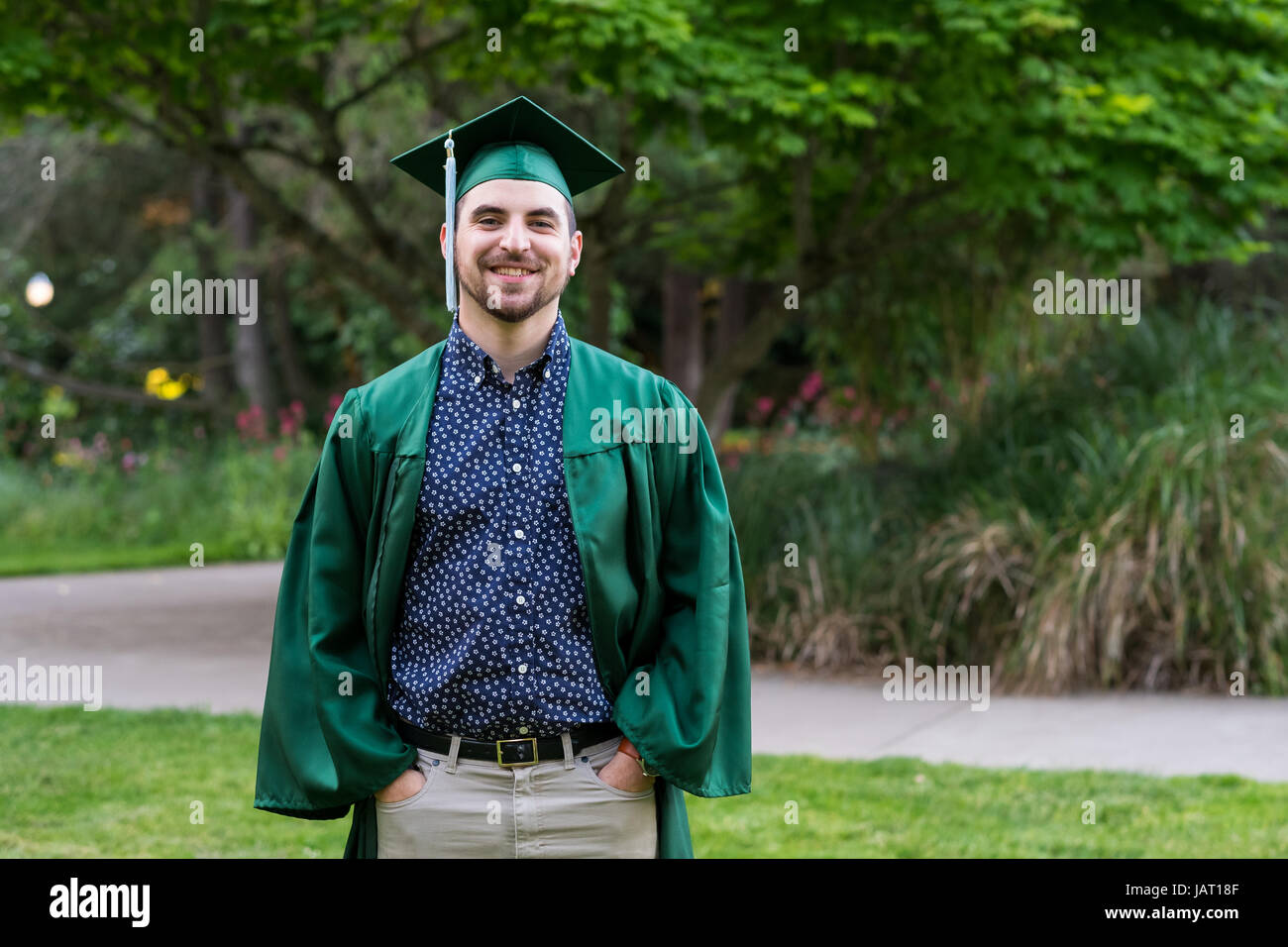 College senior poses for a graduation photo on campus in his cap and ...