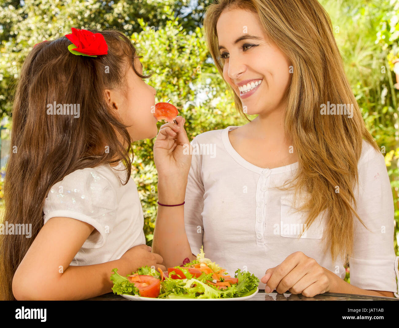 Beautiful young mother and daughter having fun eating a healthy launch ...