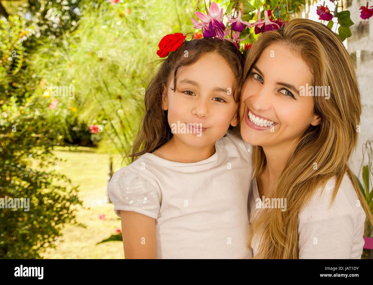 Smiling beautiful mom hugging her pretty daugher in beige dress wearing ...