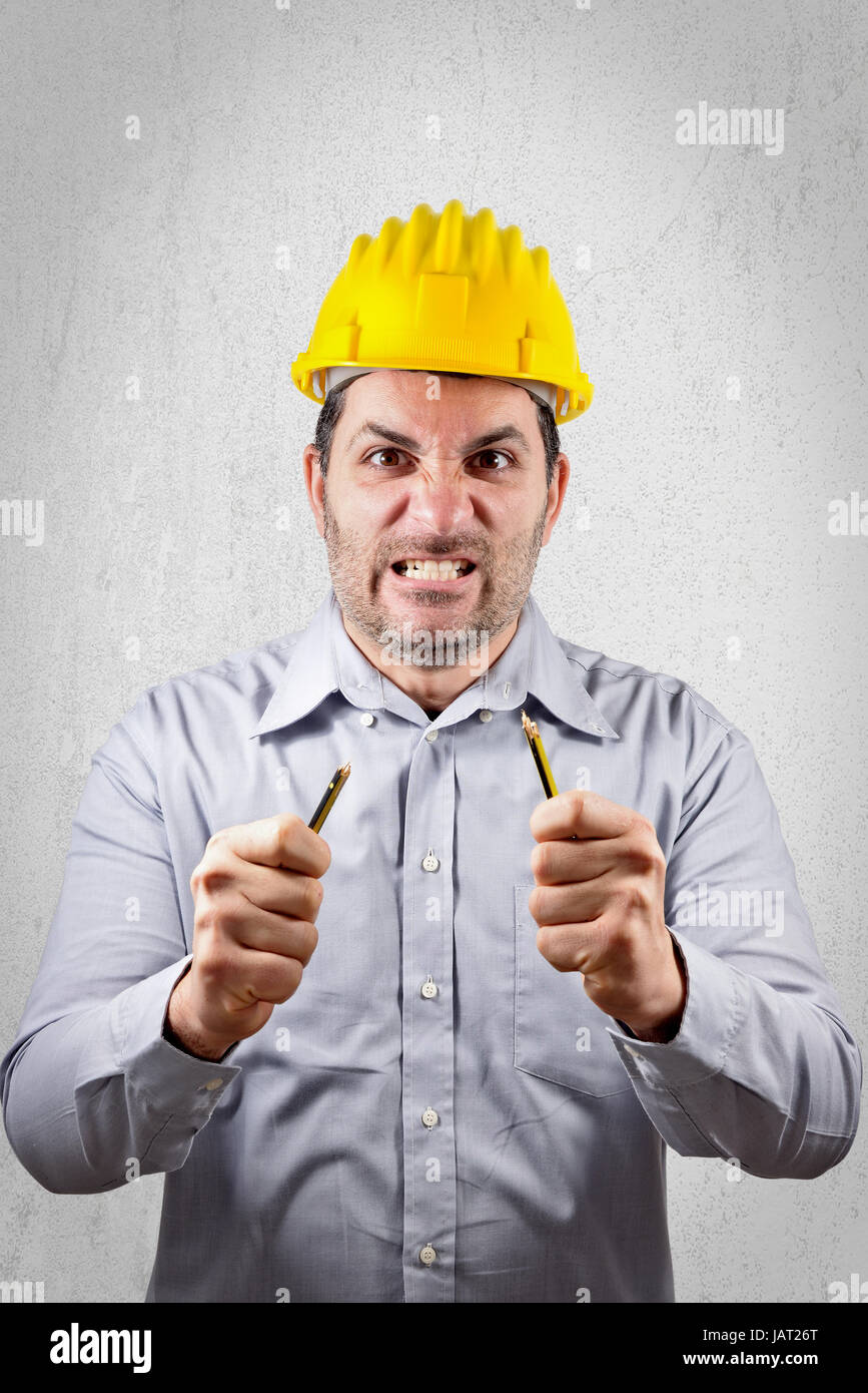 Angry Engineer with a helmet on his head, shakes the hand with a pencil ...