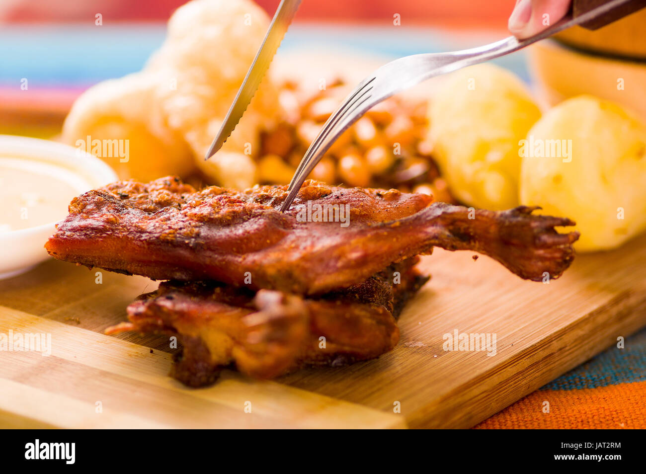 Cut pieces cooked guine pig meat lying on wooden surface next to ...