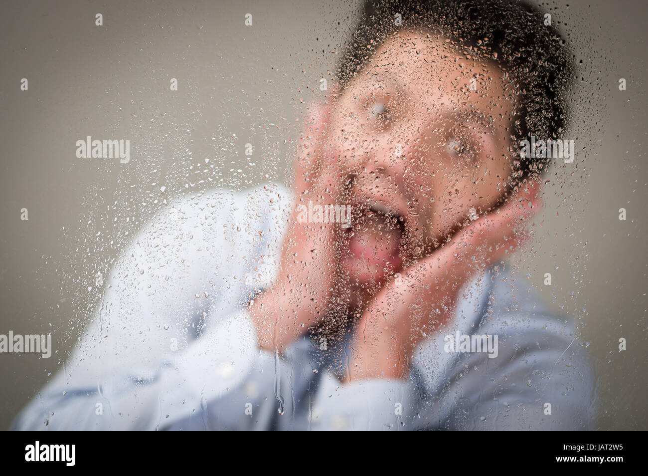 Young man screaming using his both hands in his face, behind a blurred ...