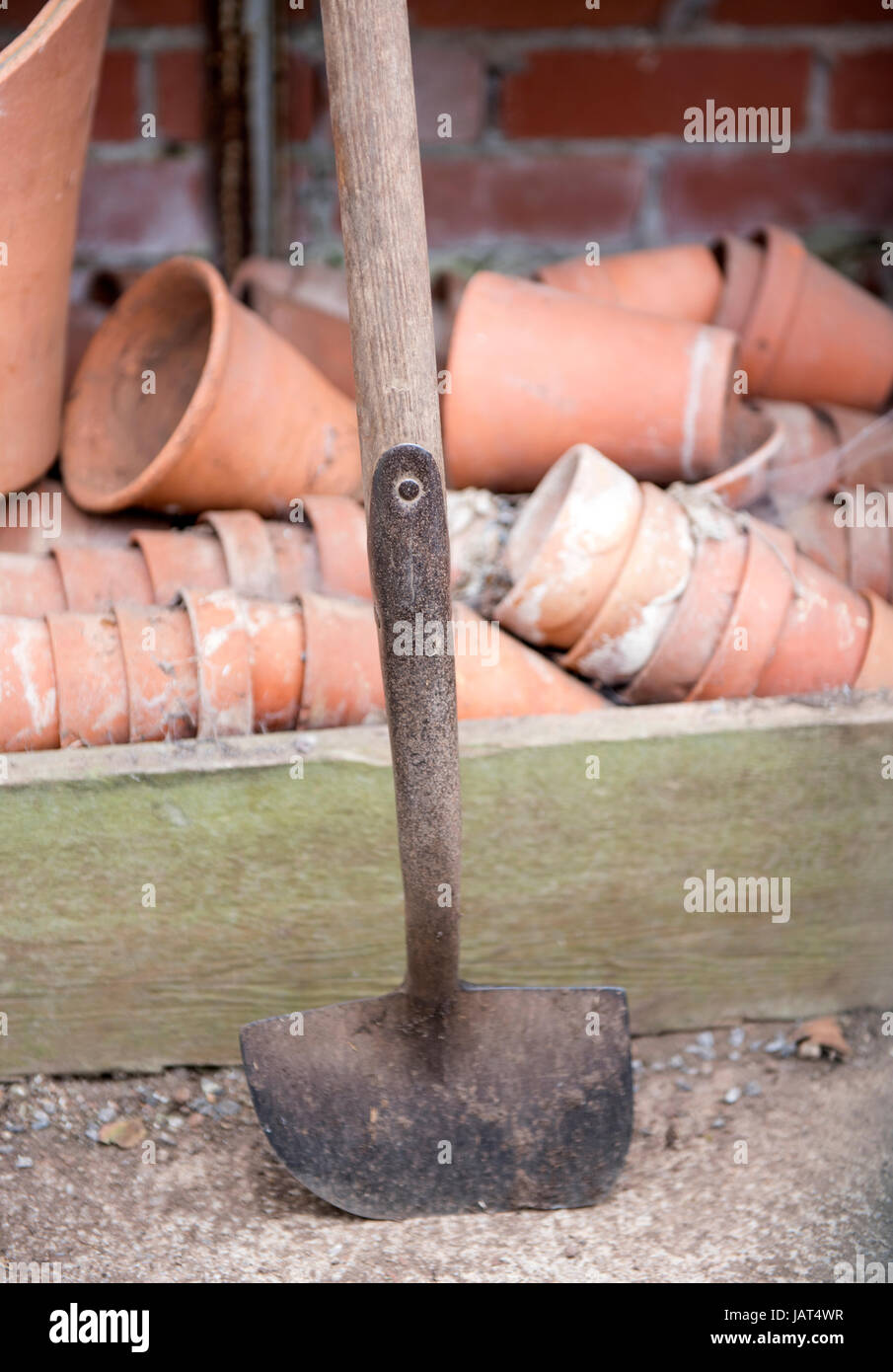 A traditional spade in a greenhouse with old fashioned clay pots Stock ...