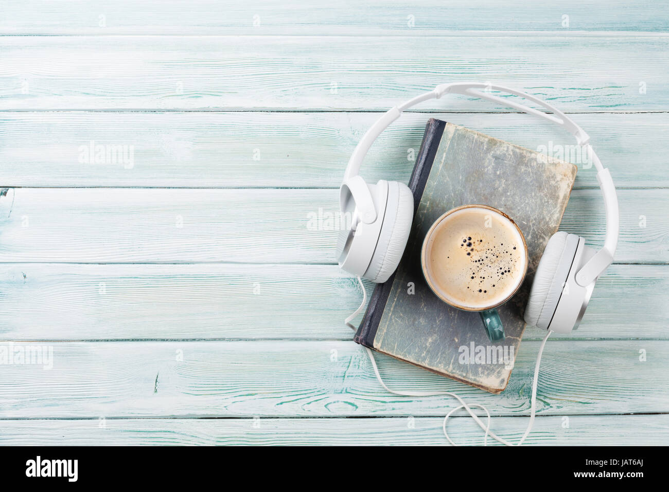 Audio book concept. Headphones, coffee and old book over wooden table ...