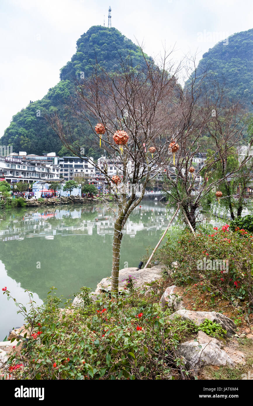 YANGSHUO, CHINA - MARCH 30, 2017: tree with lanterns on waterfront in ...