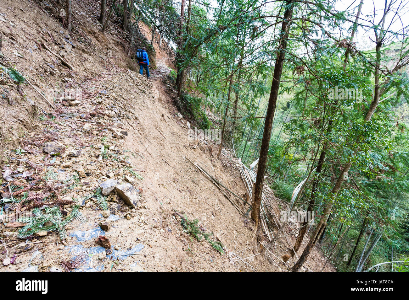 travel to China - tourist walks on path through mudslide on mountain ...