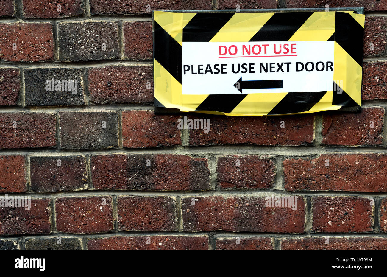 Do Not Use Please use next door sign on old brick wall Stock Photo - Alamy