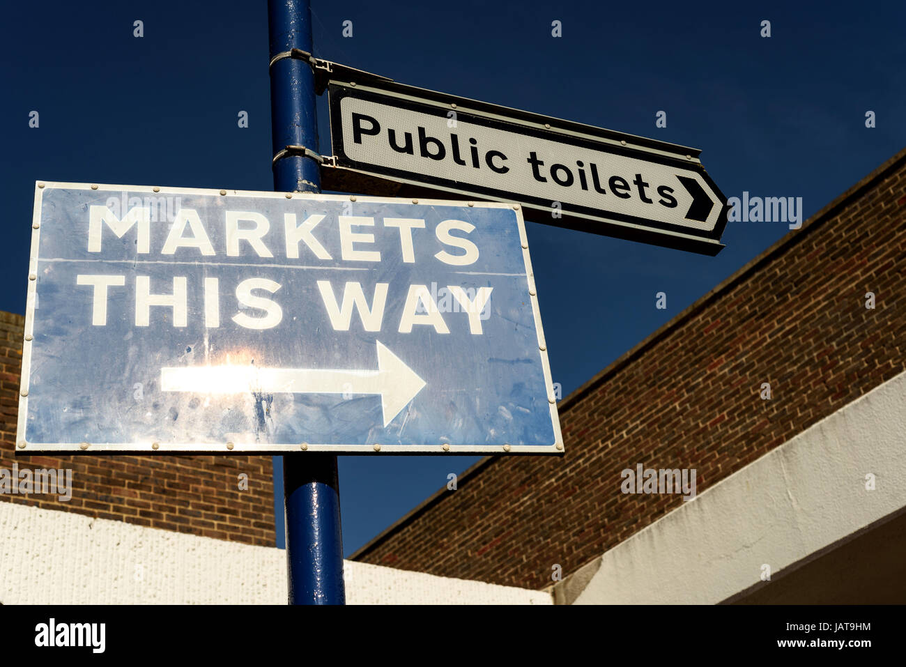 Public Toilets direction sign and markets this way sign with a blue sky ...