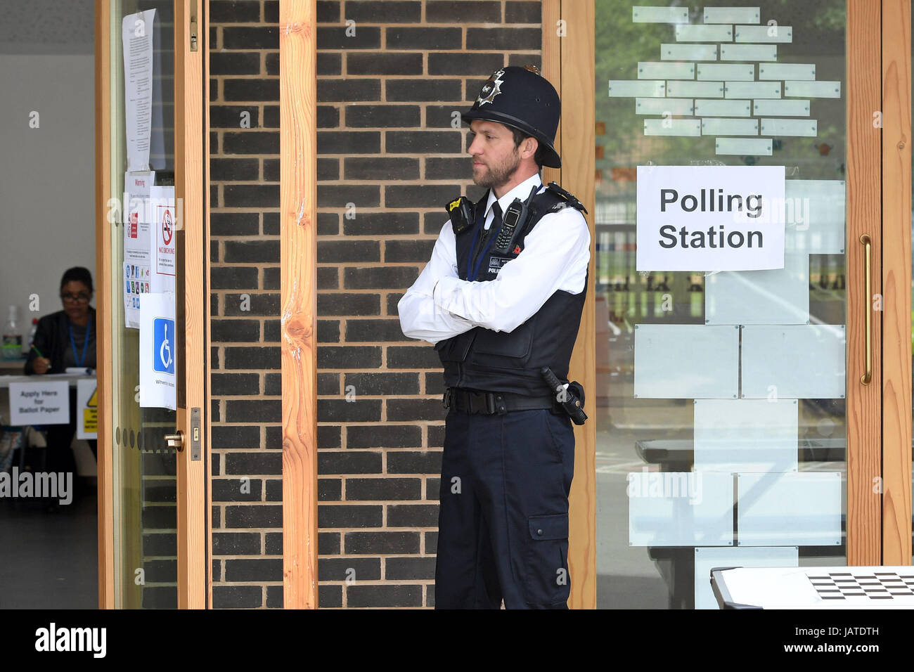 A police officer is stationed outside a polling station at Cubitt Town ...