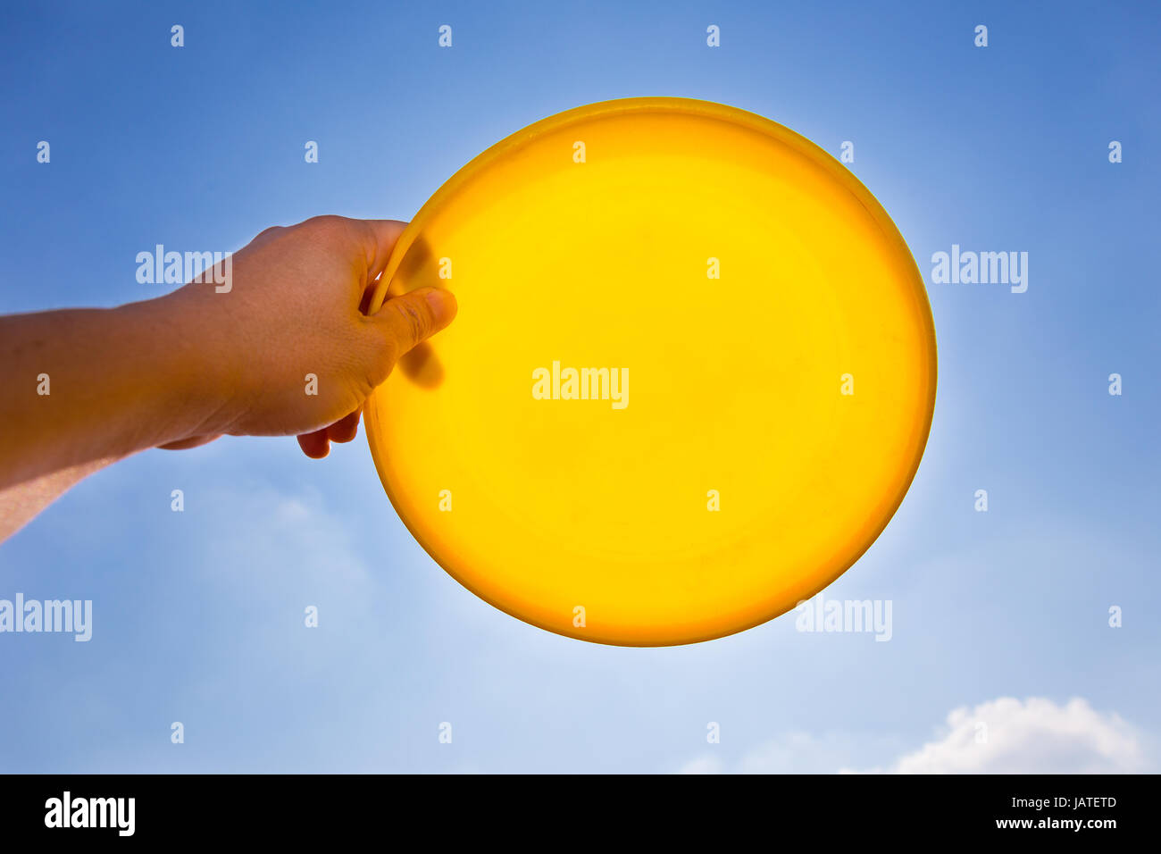 male hand catching, holding, yellow frisbee disc against blue sky ...
