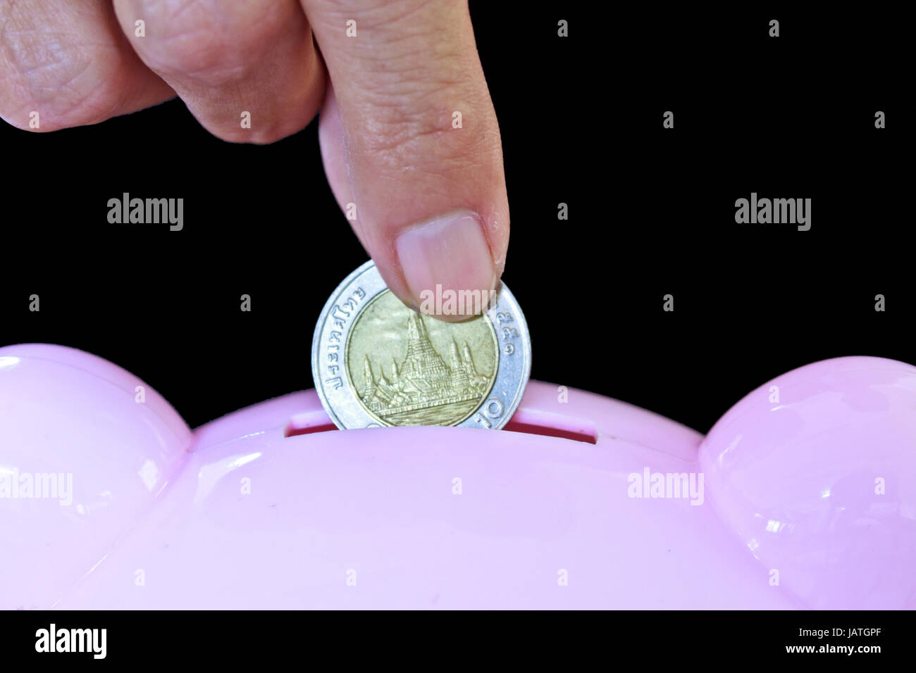 Hand inserting coin into piggy bank Stock Photo - Alamy