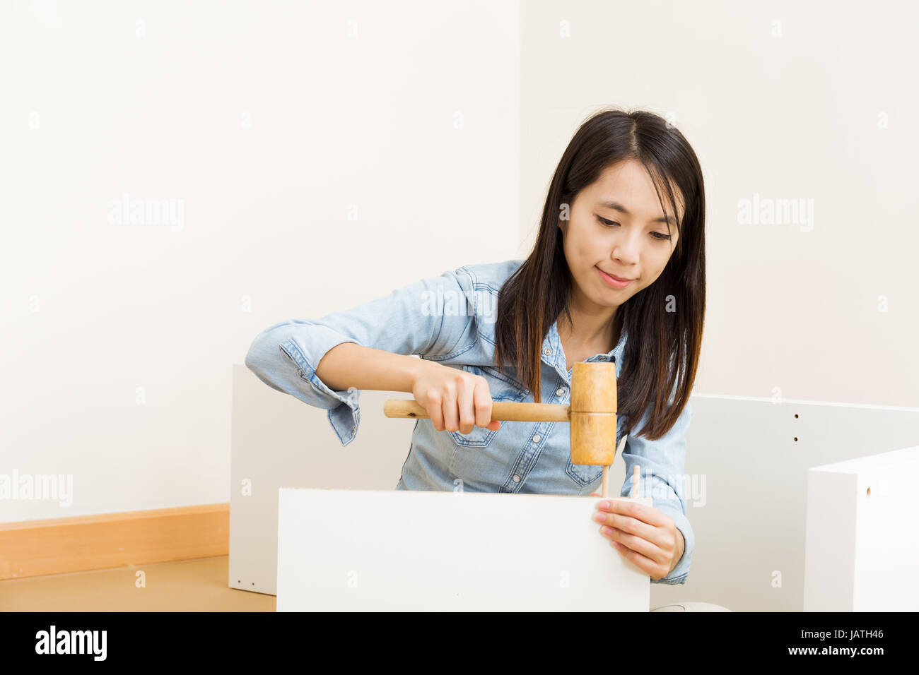 Asian woman using hammer for closet assembling Stock Photo - Alamy
