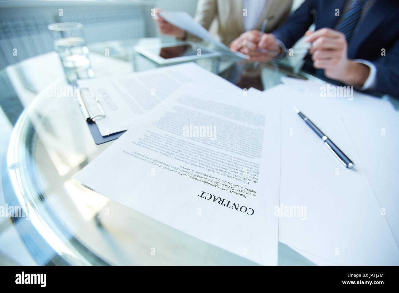 Business documents and pen at workplace with working people on ...