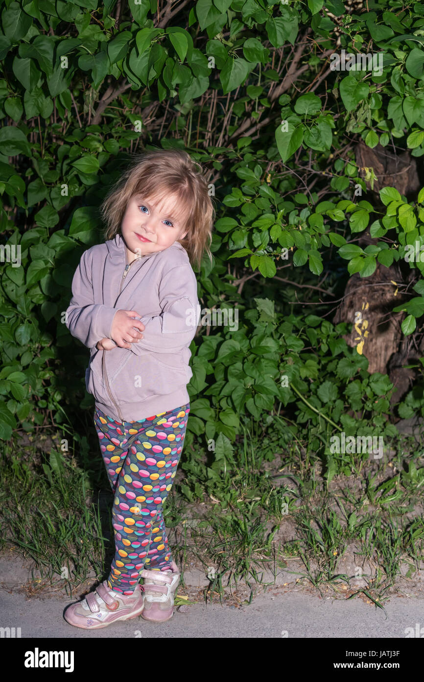 Portrait of a cute little girl crossed legs, in the evening, near ...