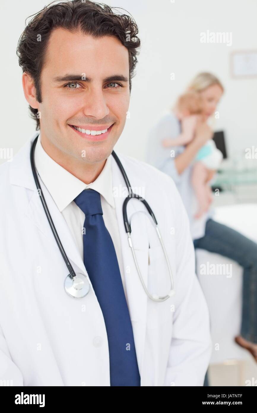 Smiling doctor with mother and her baby behind him Stock Photo - Alamy