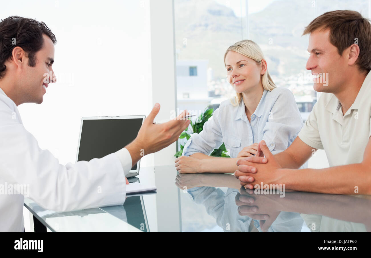 Side view of doctor talking with a couple Stock Photo - Alamy