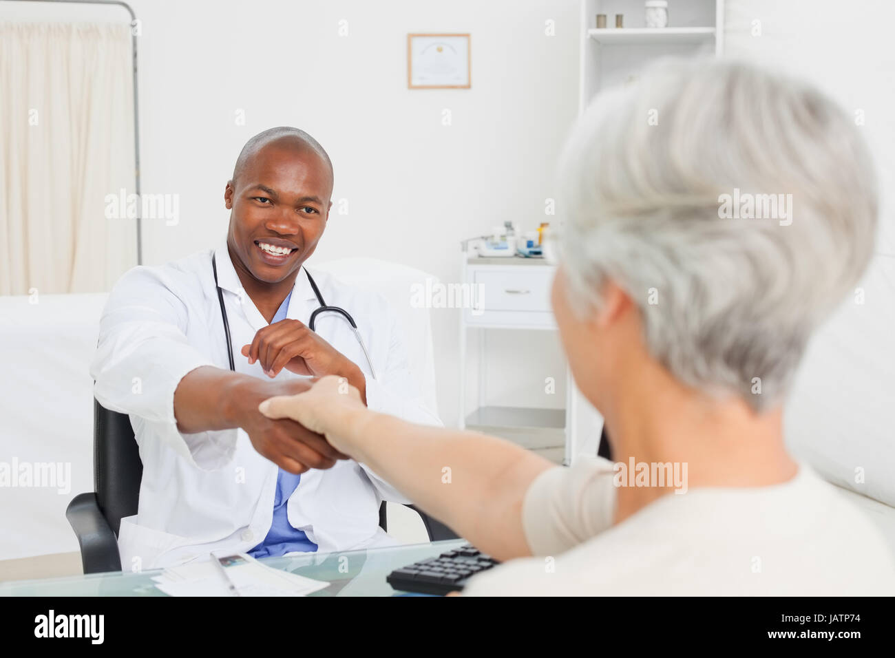 Smiling doctor shaking his patients hand Stock Photo - Alamy