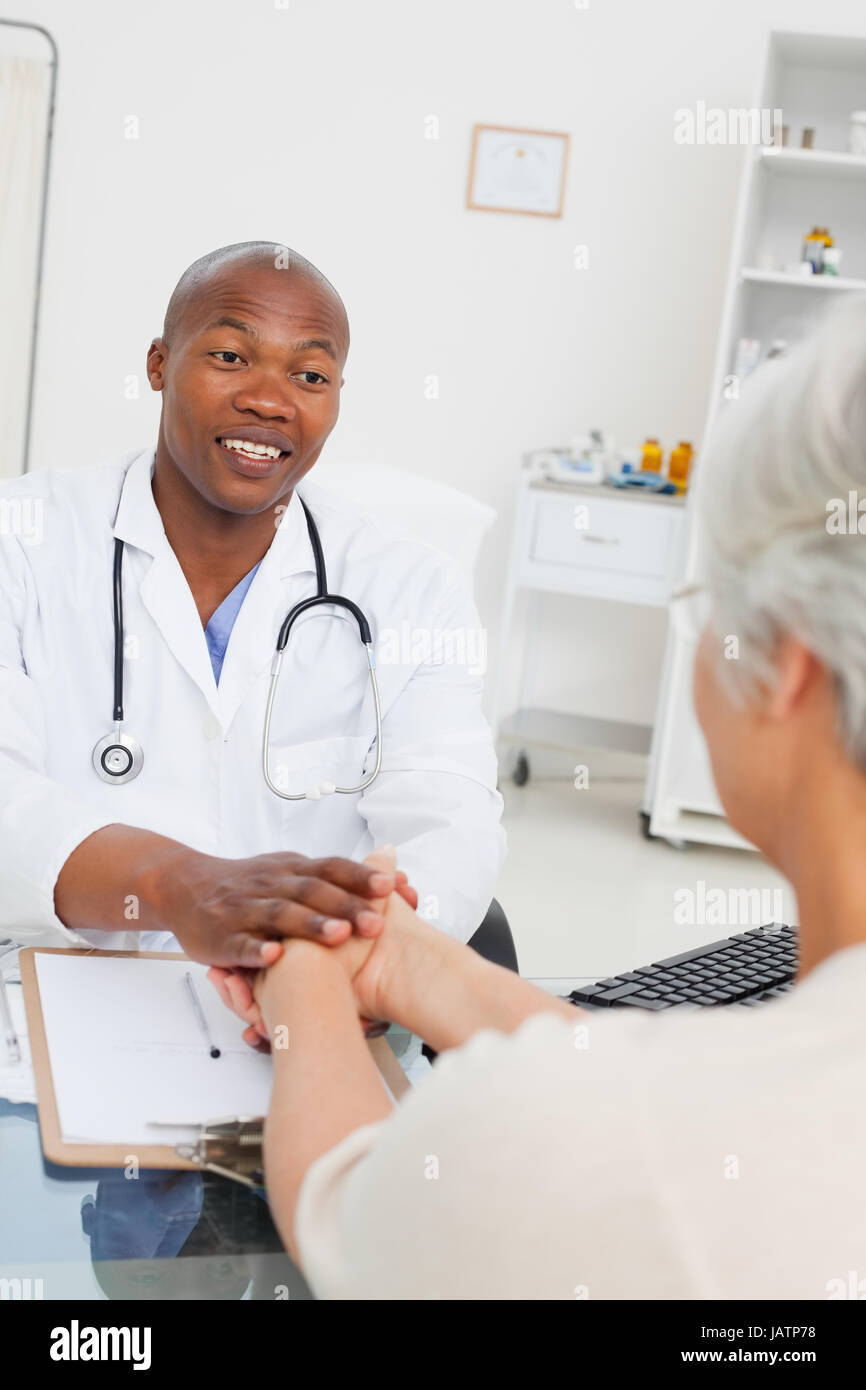 Doctor holding his patients hands while talking Stock Photo - Alamy