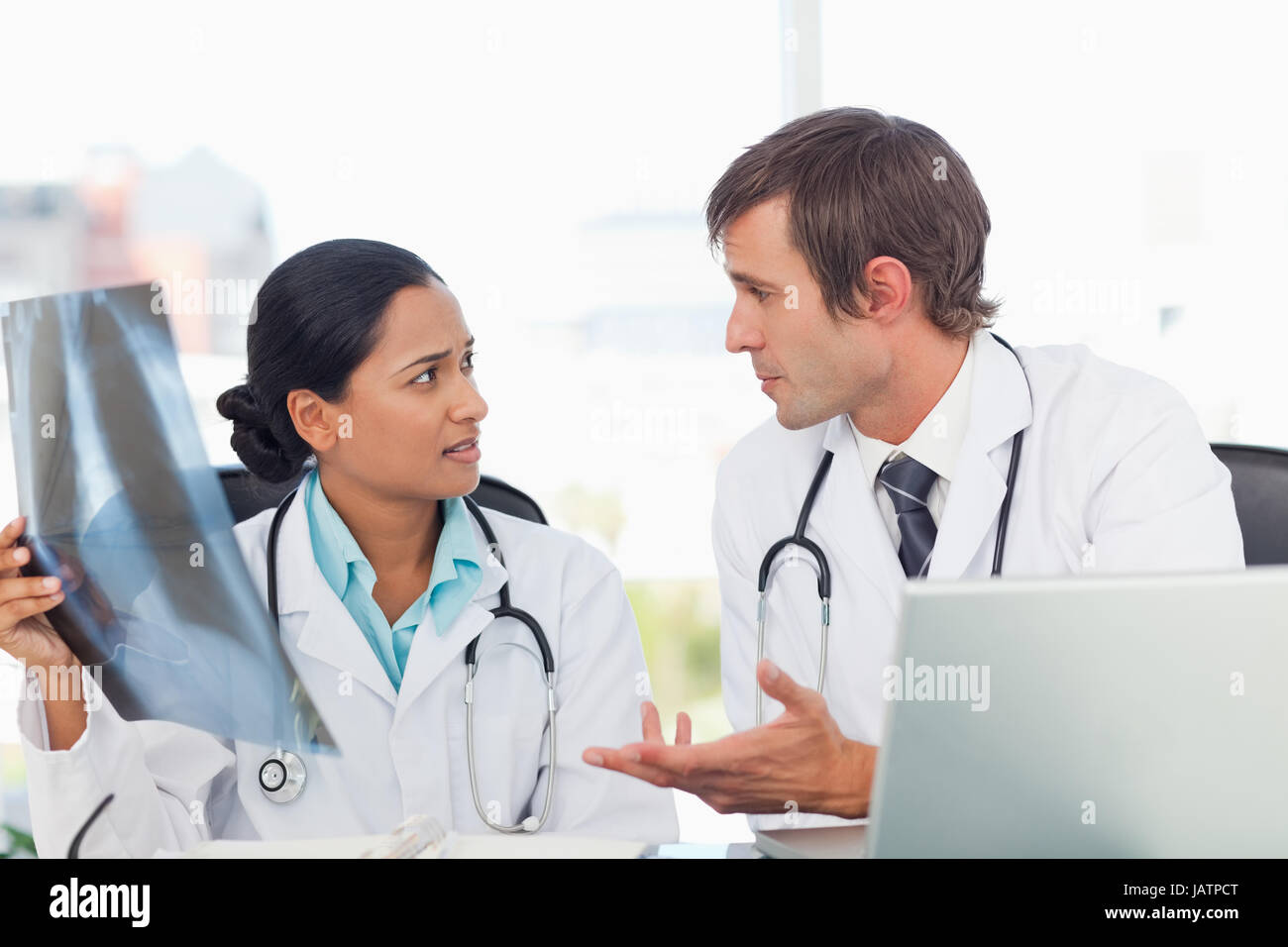 Serious doctors talking to each other about an x-ray Stock Photo - Alamy