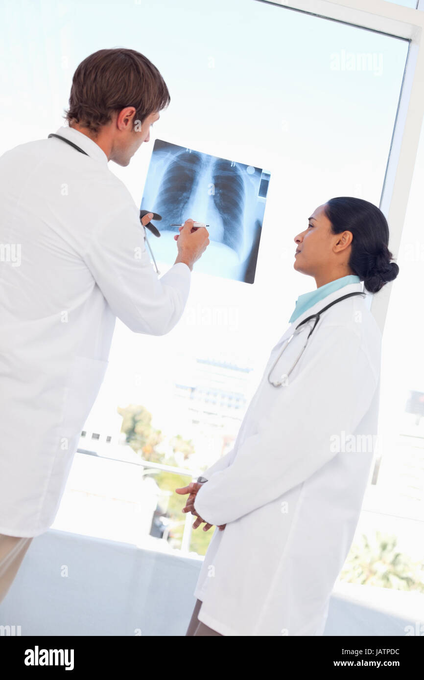 Rear view of two doctors looking at an x-ray in front of the window ...