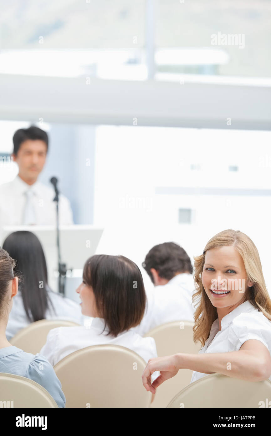 Close-up of a smiling woman looking behind her during a presentation ...