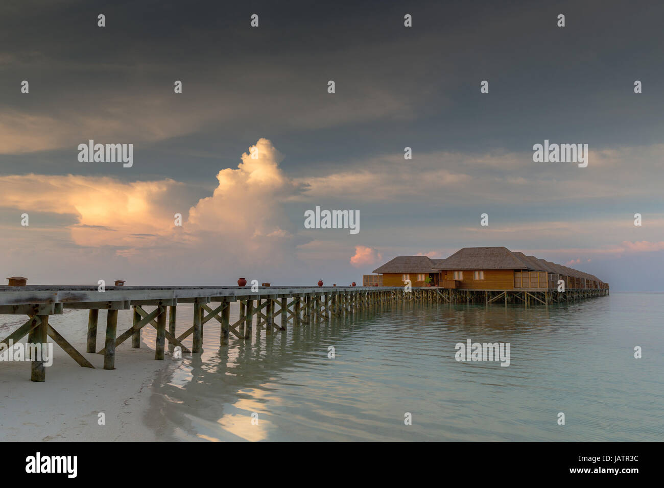 Maldives beach villas in sunset scenery with strong cloud formation ...
