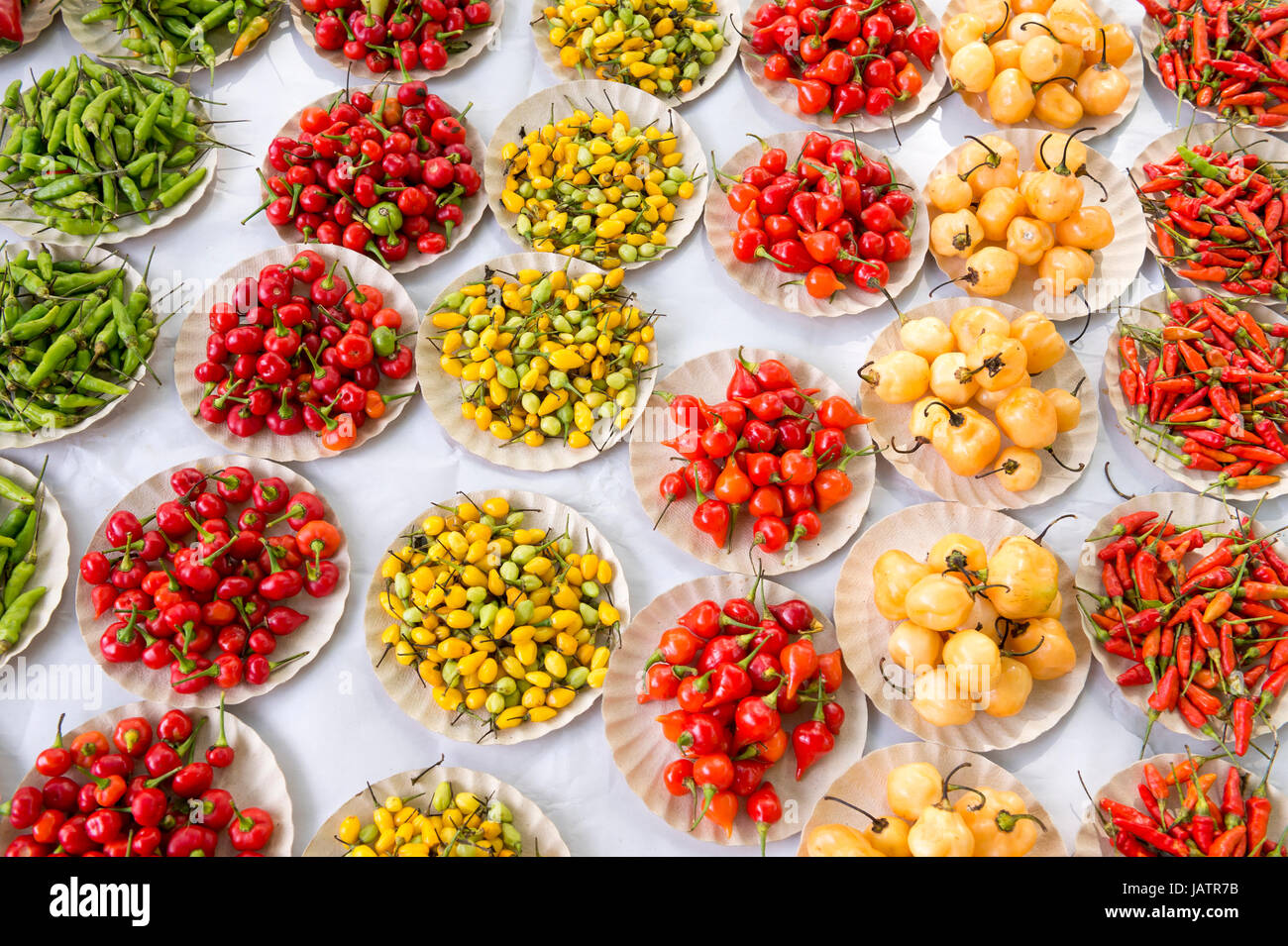 Colorful hot peppers in bright red, yellow, and green piles at farmers ...