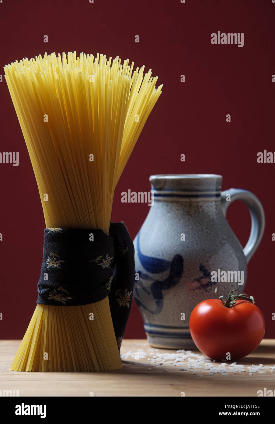 The image shows a still life with spaghetti, a tomato, rice and a jar ...