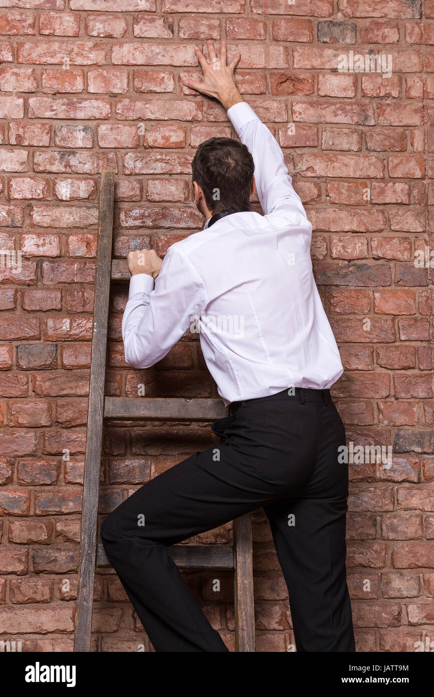 Man at the end of his search up against a brick wall standing balanced ...