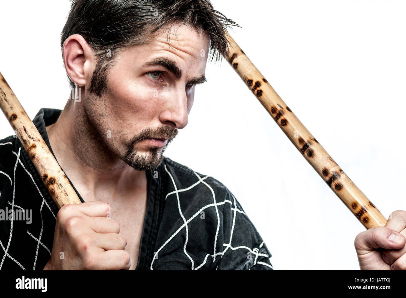 Martial arts master with black combat dress and two short bamboo sticks ...