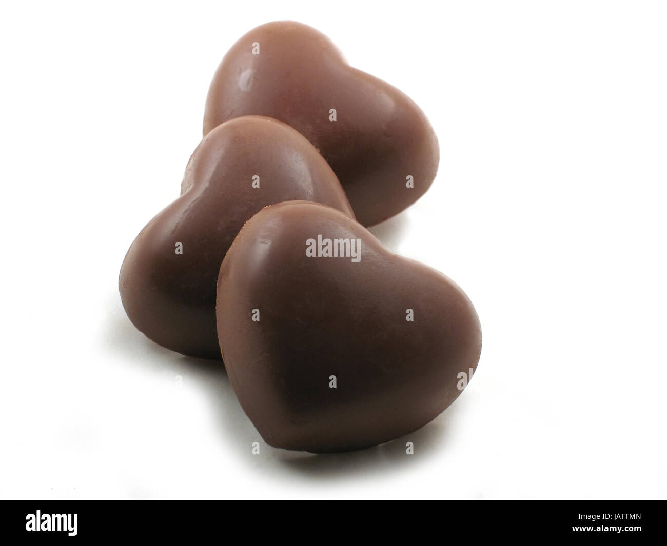 Three chocolate heart candies on white Stock Photo - Alamy